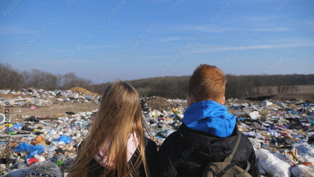 Rear view of young girl and boy stands against the blurred background ...