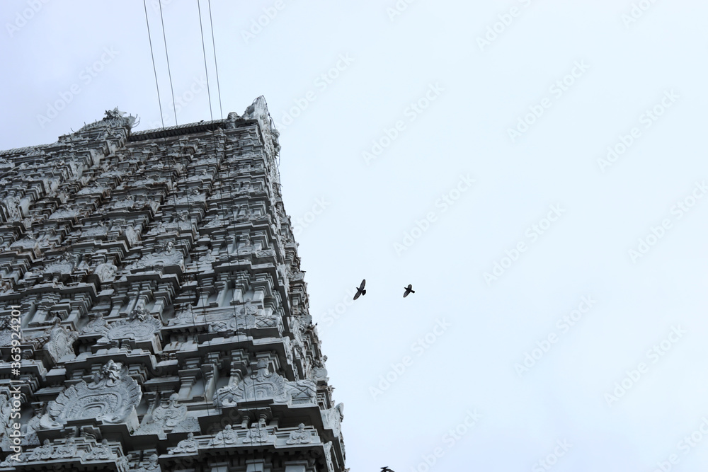 Beautiful view of the tower in the Hindu temple with birds flying on ...