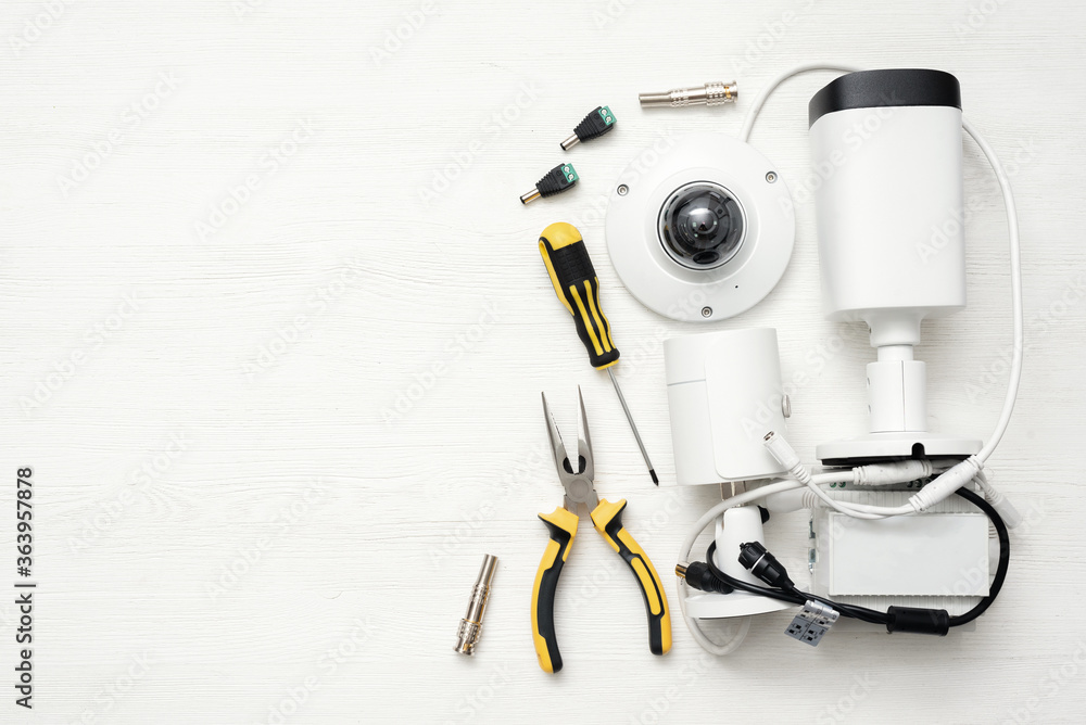 Modern white security cameras and work tools on the table background ...