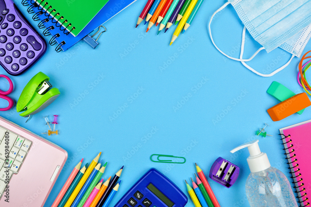 School supplies and COVID 19 prevention items. Frame on a blue paper ...