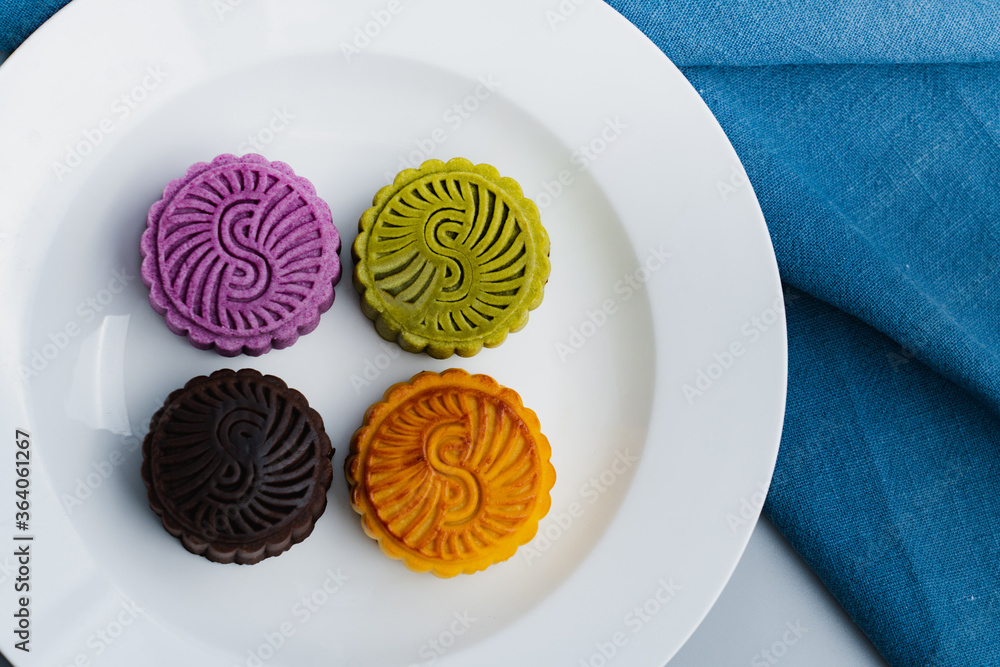 Colorful moon cakes are placed on white plates. Chinese traditional ...