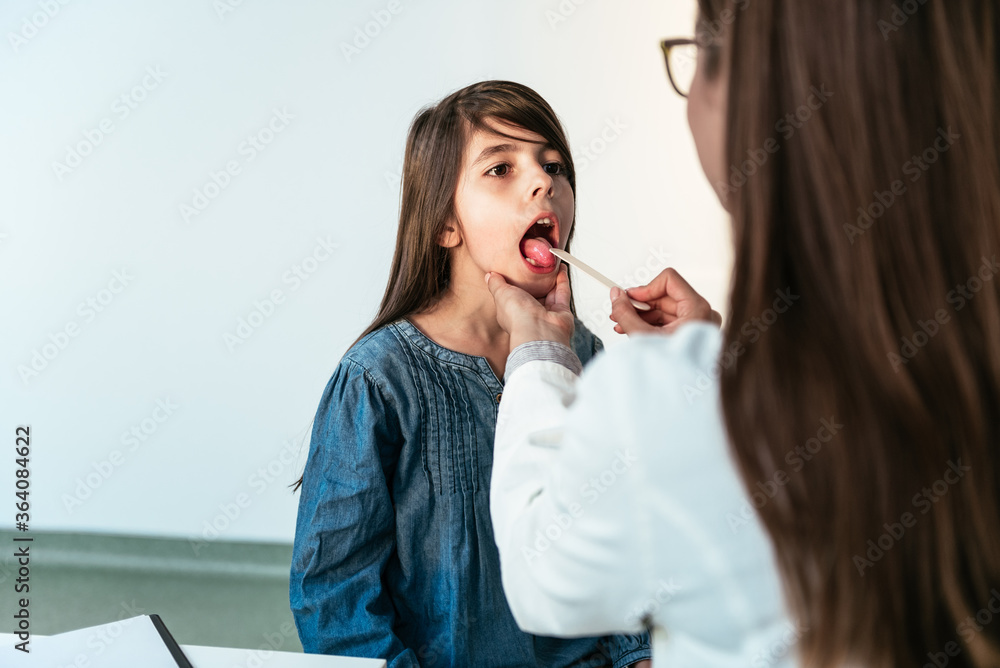 Woman doctor examining little girl at hospital checking the sore throat ...
