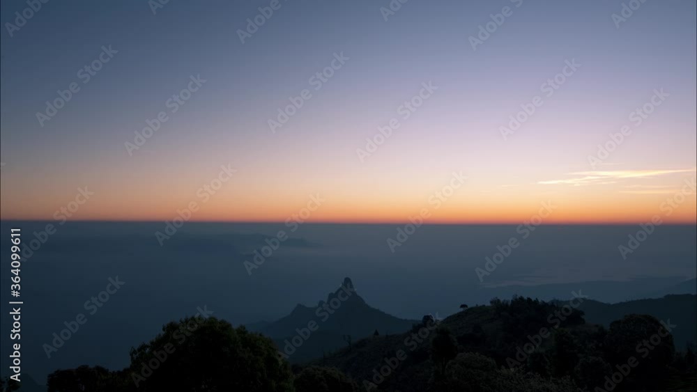 Time-lapse of the golden hour sun-rise behind the mountains, while the clouds move below the ...