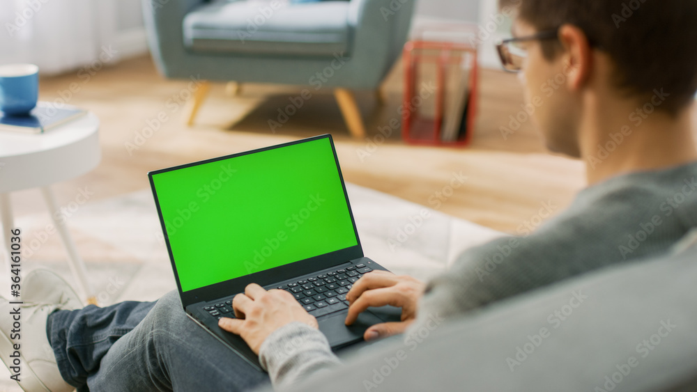 Over the Shoulder Shot: Young Man Wearing Glasses Works on a Laptop ...