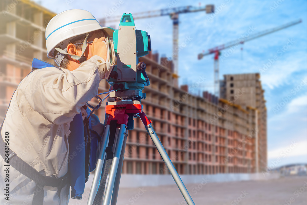 Surveyor in a white helmet next to theodolite. Measuring work in ...