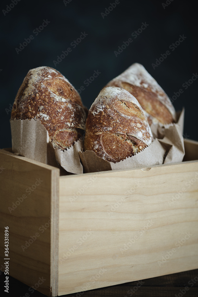 Baked bread of sourdough. French loaves of bread in wooden box. The ...