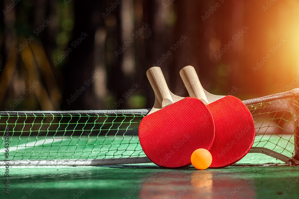 Table tennis rackets and ball on a green table and net, sports game ...