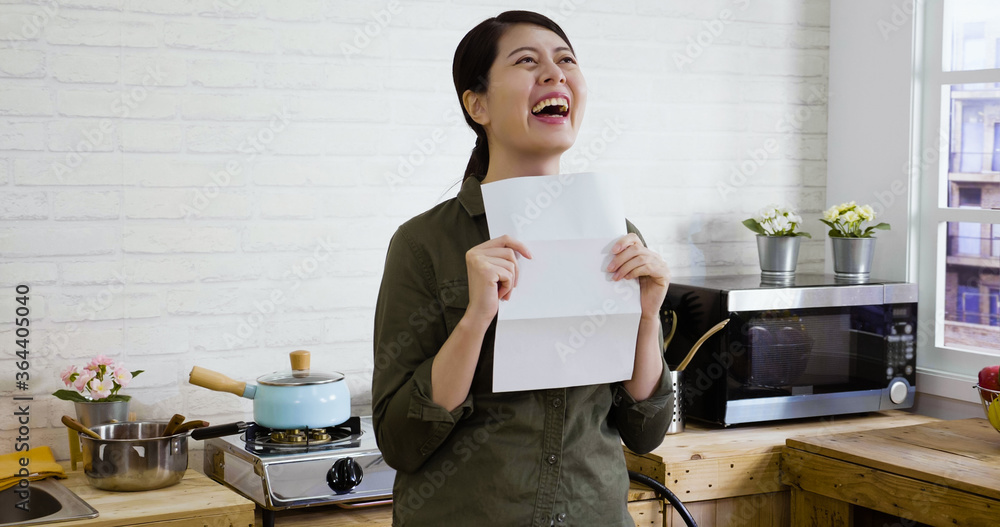 Excited girl reading letter knowing good news while standing in kitchen ...