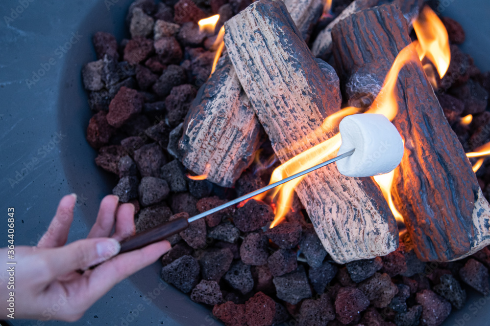 Roasting marshmallow over a gas fire while glamping Stock Photo | Adobe ...