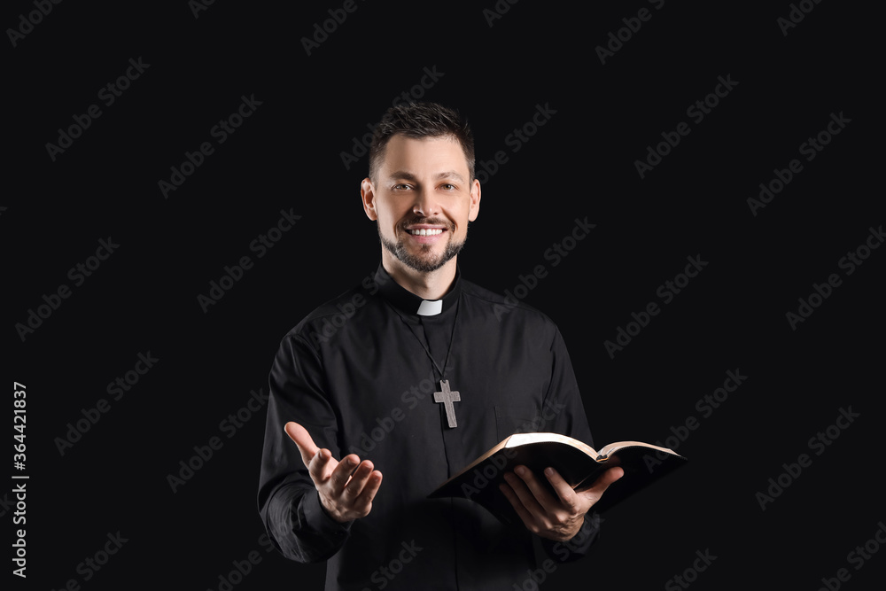 Handsome priest with Bible on dark background Stock Photo | Adobe Stock