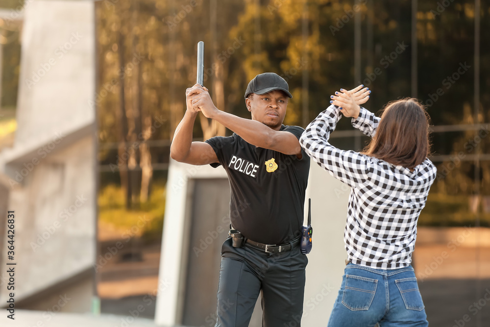 Aggressive African-American police officer mistreating woman outdoors ...
