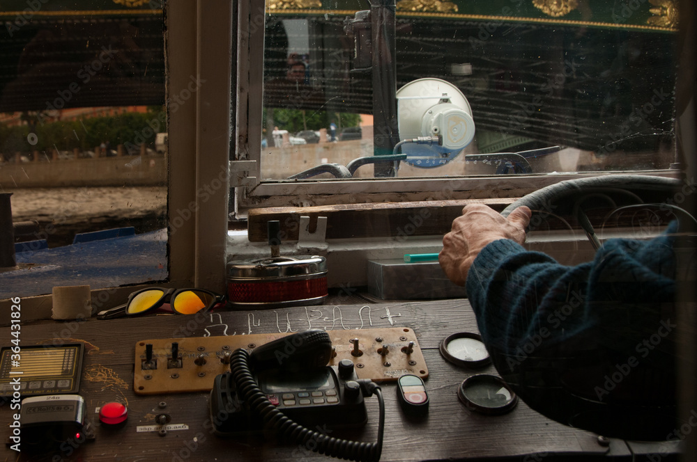 Deckhouse of the ship. Helmsman‘s hand on a steering wheel. Looking ...