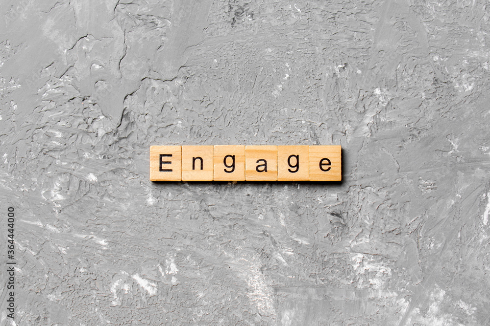 ENGAGE word written on wood block. ENGAGE text on cement table for your ...