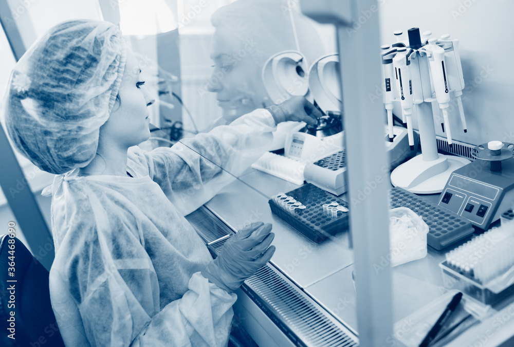 A young female scientist works in a sterile genetic or bacteriological ...
