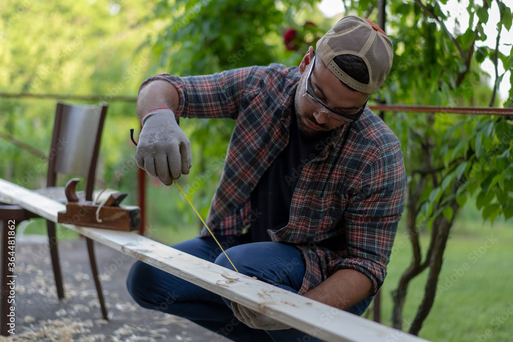 Handsome young man carpenter installing a wood fence outdoor terrace in ...