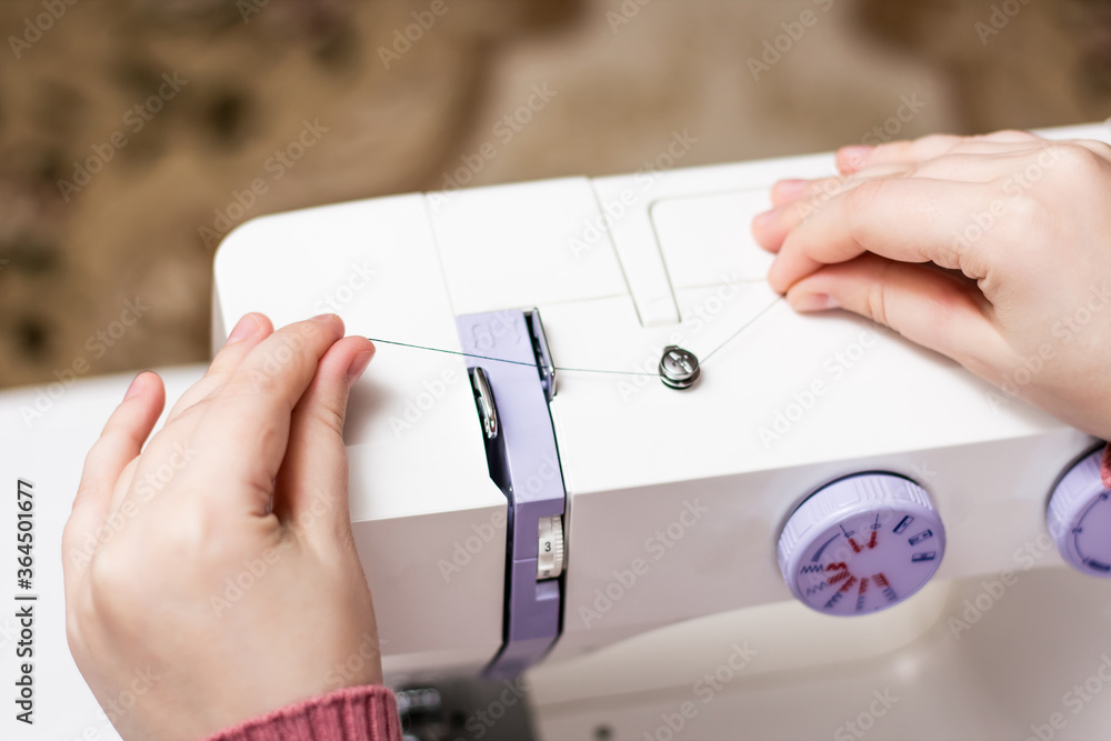 The girl is threading the needle of a sewing machine. Close plan. White ...