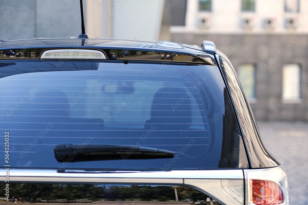 Back window of black car parked on the street in summer sunny day, rear ...