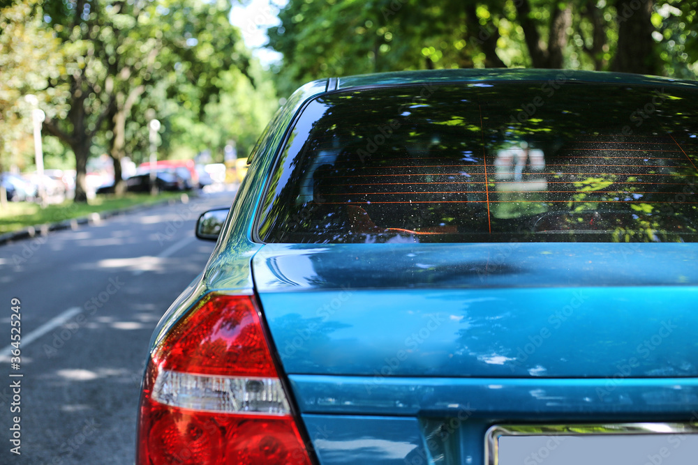 Back window of blue car parked on the street in summer sunny day, rear ...