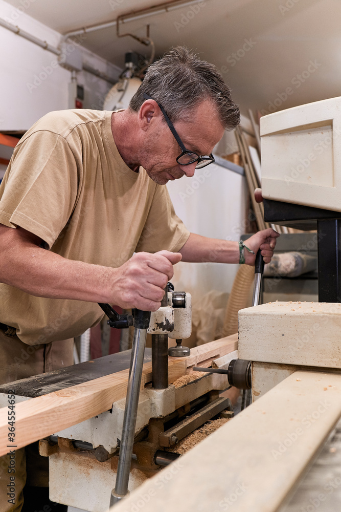 Low angle of attentive middle aged male woodworker in glasses and ...