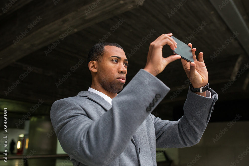 Back view of black man in suit using smartphone and taking photo of ...