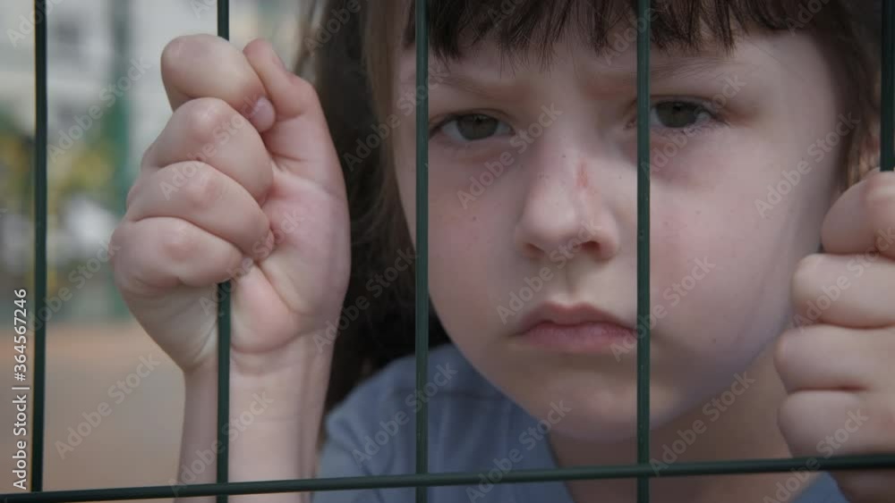 Childhood by fence. Children's loneliness. Sad little girl with a ...