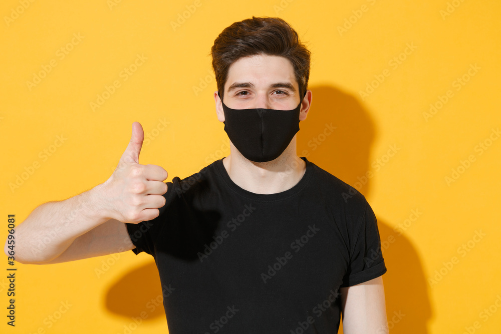 Young guy in casual black t-shirt face mask isolated on yellow ...