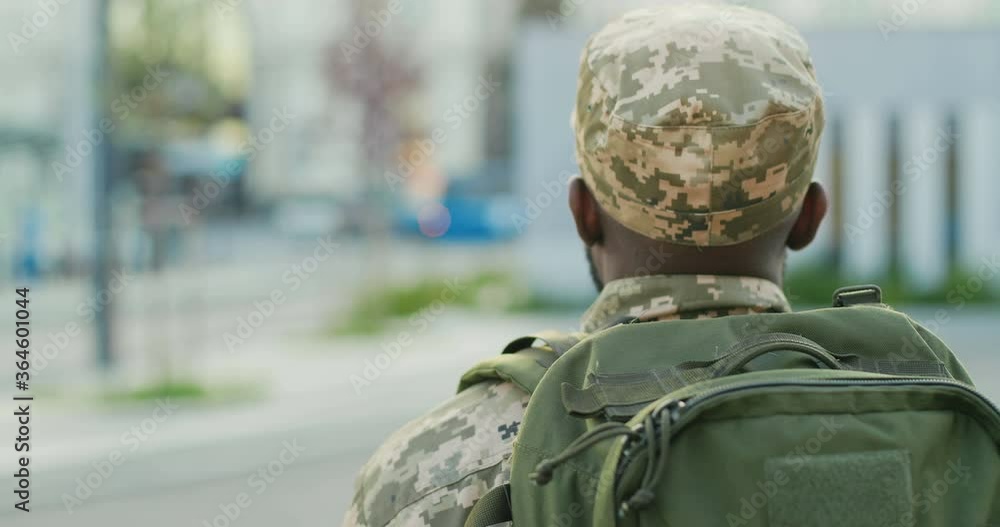 Rear of African American young male soldier in uniform, hat and with ...