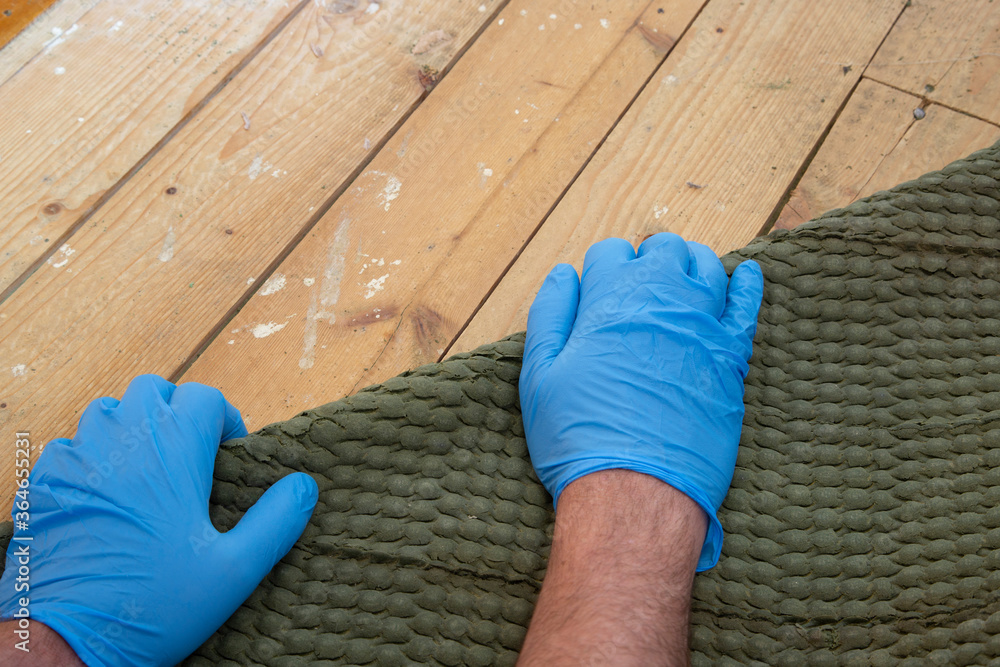 Man pulling up and removing carpet underlay from a wooden floor. Home ...