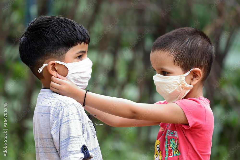 Indian girl helping brother wearing face mask to prevent covid-19 ...