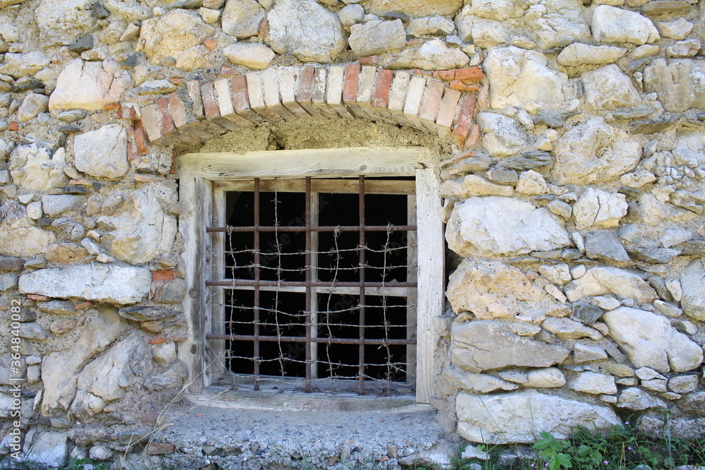 Window with railing in an old stone wall, dark interior, brick arch ...