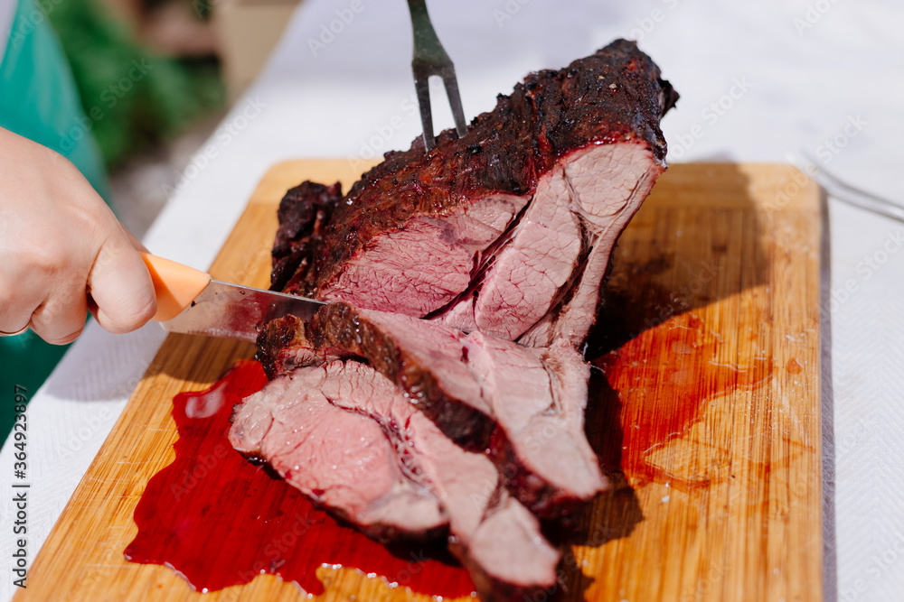 Beef steak with blood. Grilled beef with blood. The cook cuts the ...