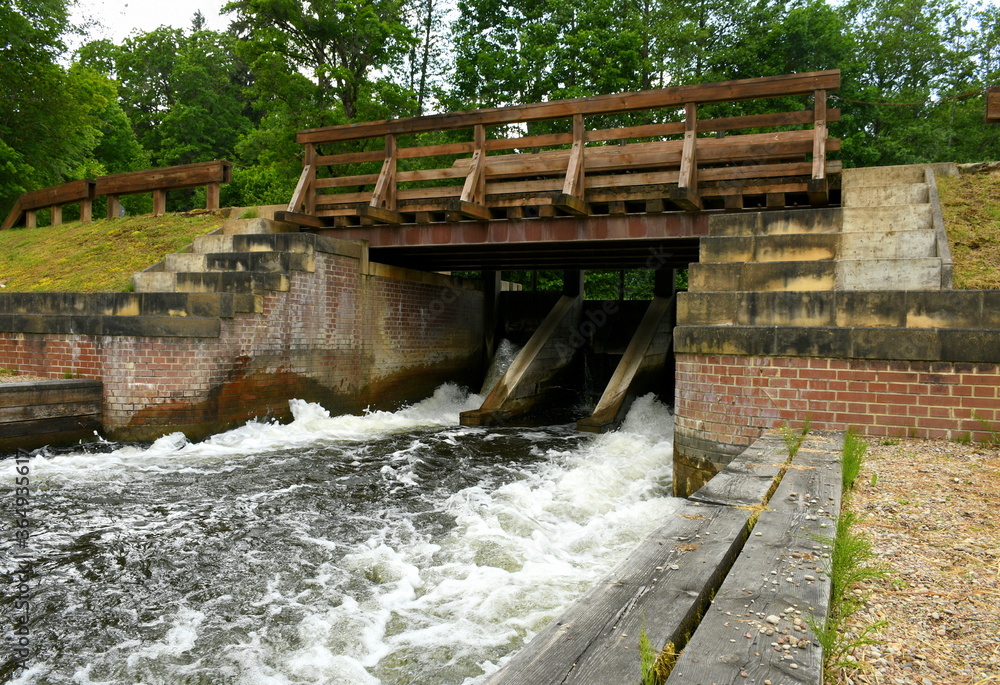 Close up on a dam used for regulating water level with a wooden bridge ...