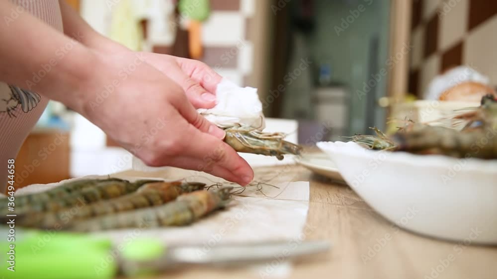 girl prepares shrimp for cooking. soaks and cuts off the antennae ...