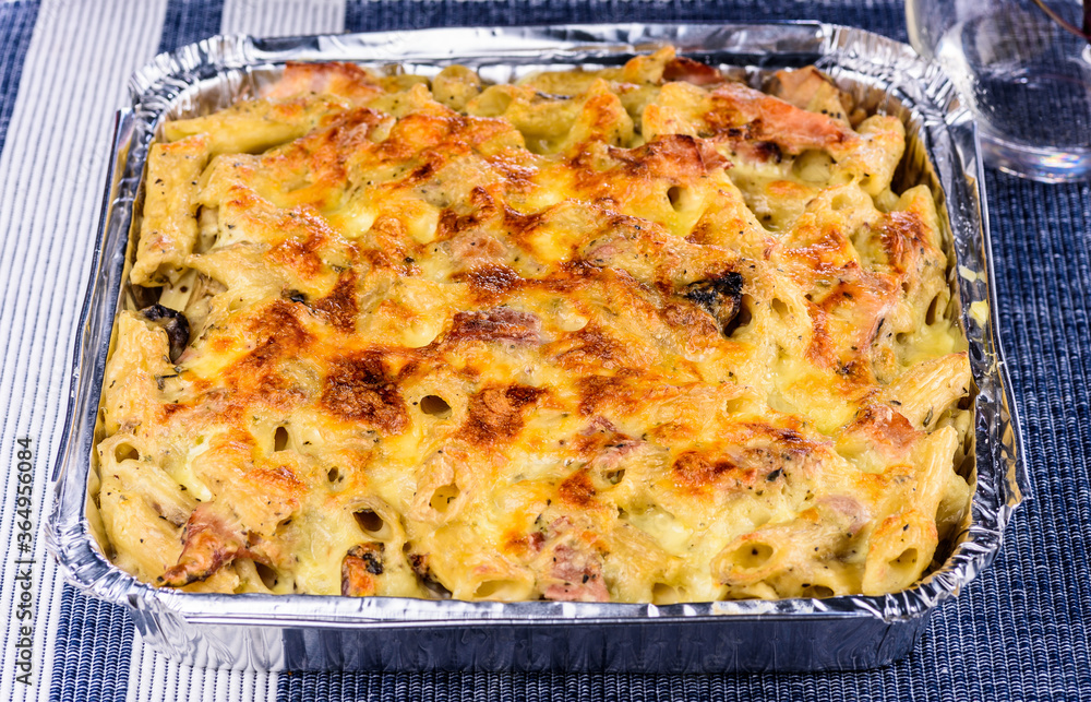 A family size take away Pasta Bake with melted cheese in a tin foil ...