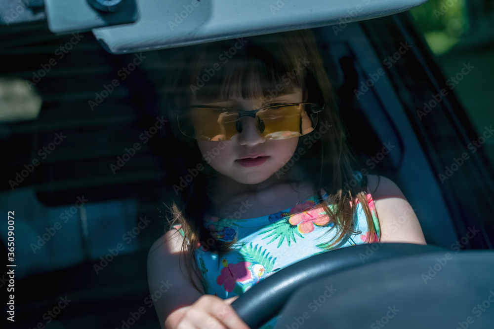 Foto de Dangers and risks of underage driving. A little child girl ...