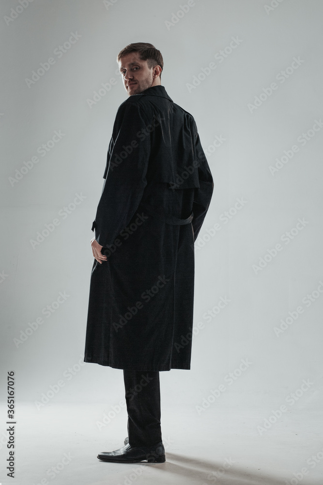 Mysterious man turned back to camera in a long dark trench coat ...