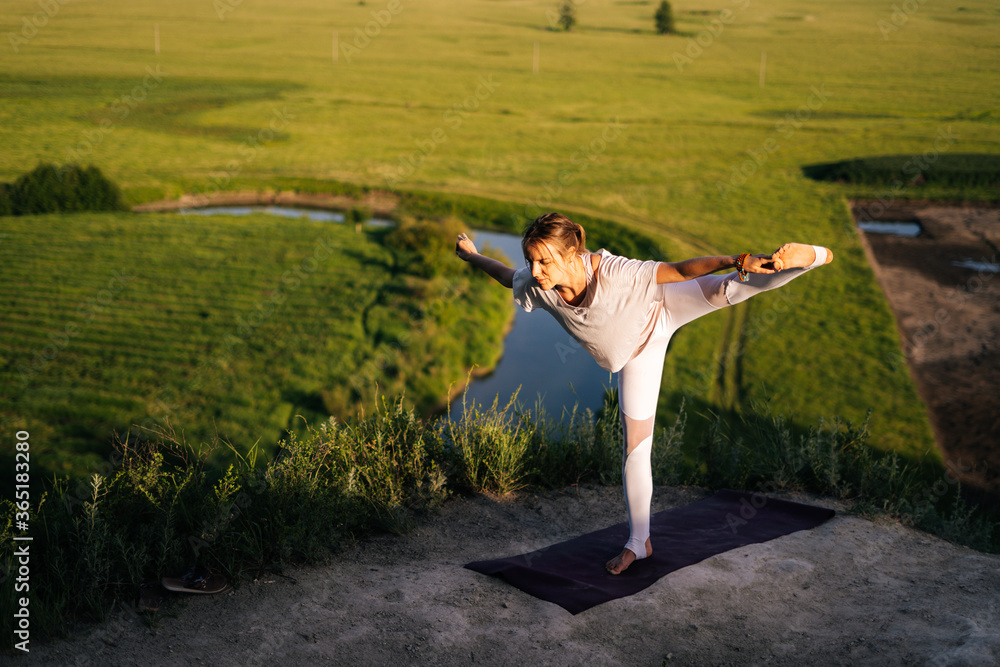 Beautiful woman practicing yoga on top of rock background of flowing ...