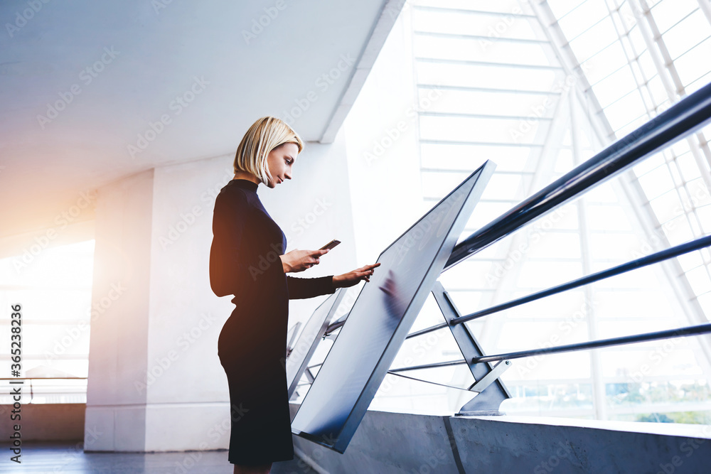 Female architect holding cell telephone while viewing 3d-visualization ...