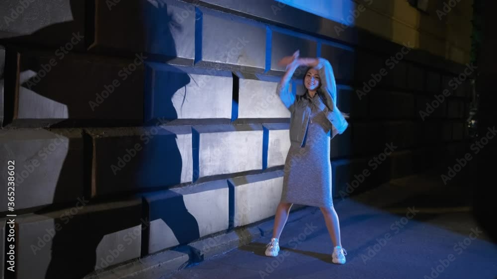 young girl dancer dancing modern street dance against the wall in the ...
