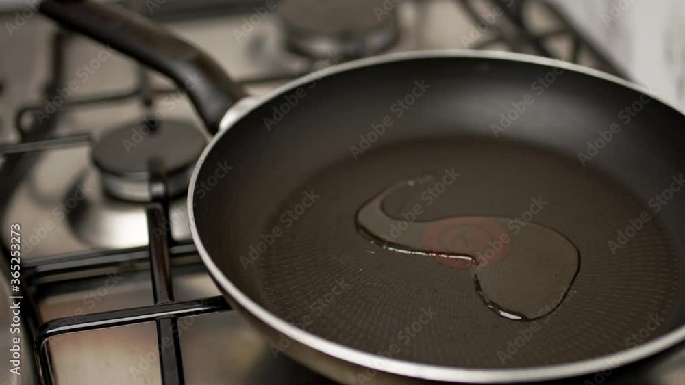 Pouring oil in a frying pan. Concept of heating the oil in a pan before ...