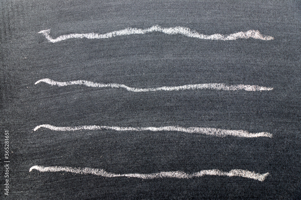 White color chalk hand drawing in set of wavy line shape on black board ...