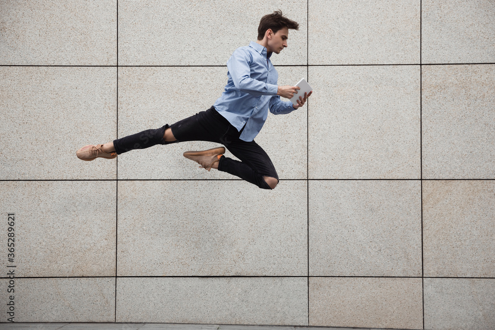 Jumping young buinessman in front of city building wall, on the run in ...
