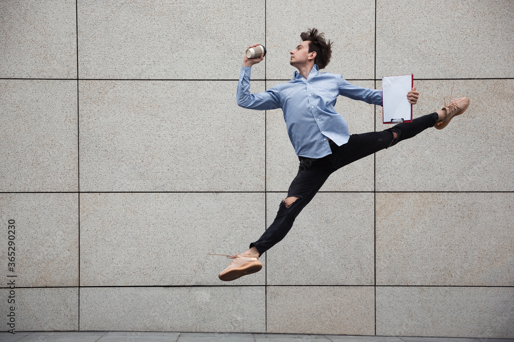 Jumping young buinessman in front of city building wall, on the run in ...