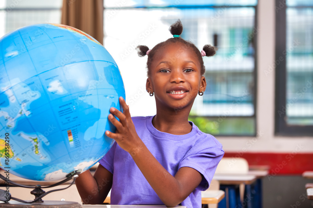 Elementary school scene. African schoolgirl using world globe in the ...