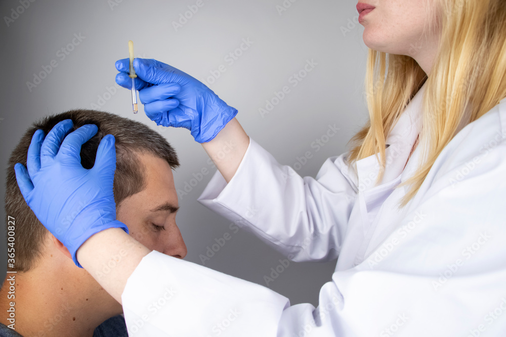 A trichologist doctor drips the serum onto the patient's hair ...