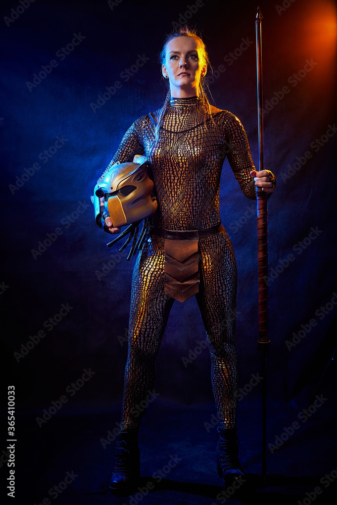 Valkyrie girl in shiny military armor and with a spear in a dark room ...