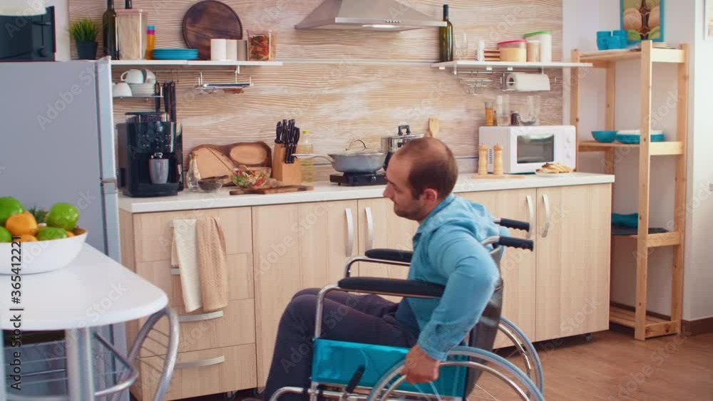 Video „Disabled man in wheelchair helping wife in kitchen. Opening ...