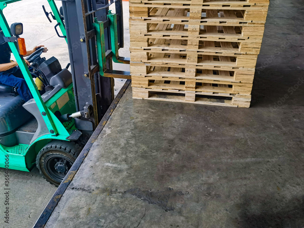 Worker driving forklift to loading and unloading wooden pallets from ...