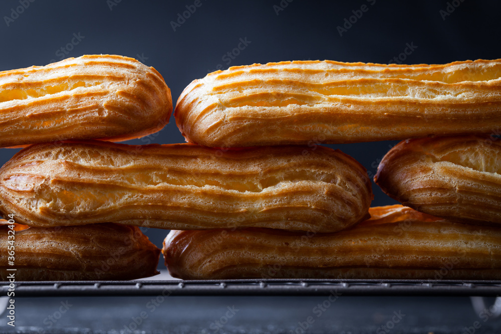 Fresh yellow toasted eclairs stacked in a pile on a pastry lattice on ...