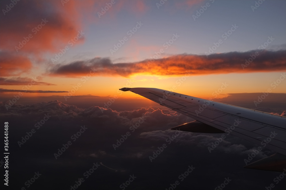 Spectacular sunset from inside an airplane over clouds a valley and a ...
